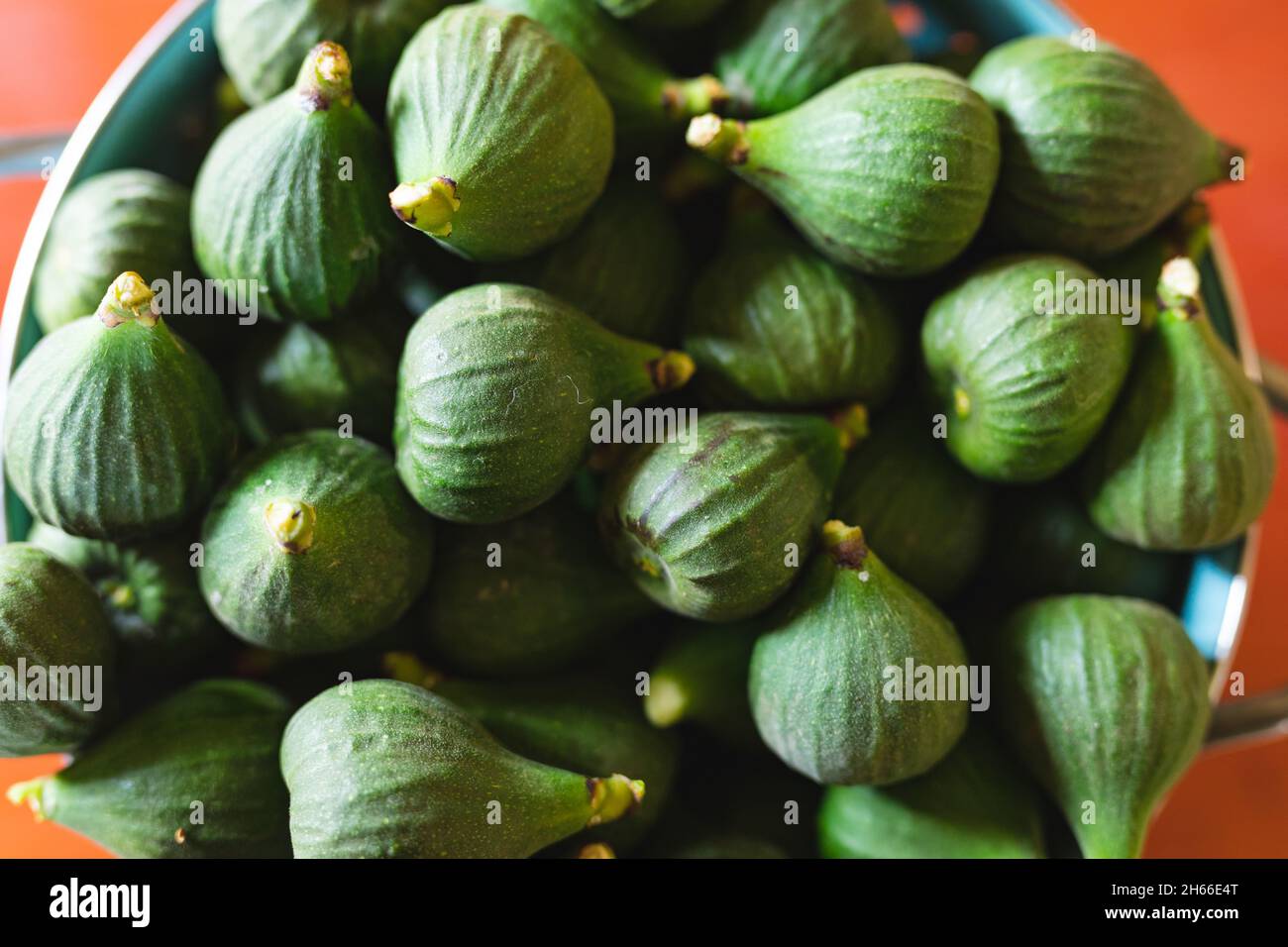 Overhead view of fresh healthy fig pile in container at kitchen counter ...