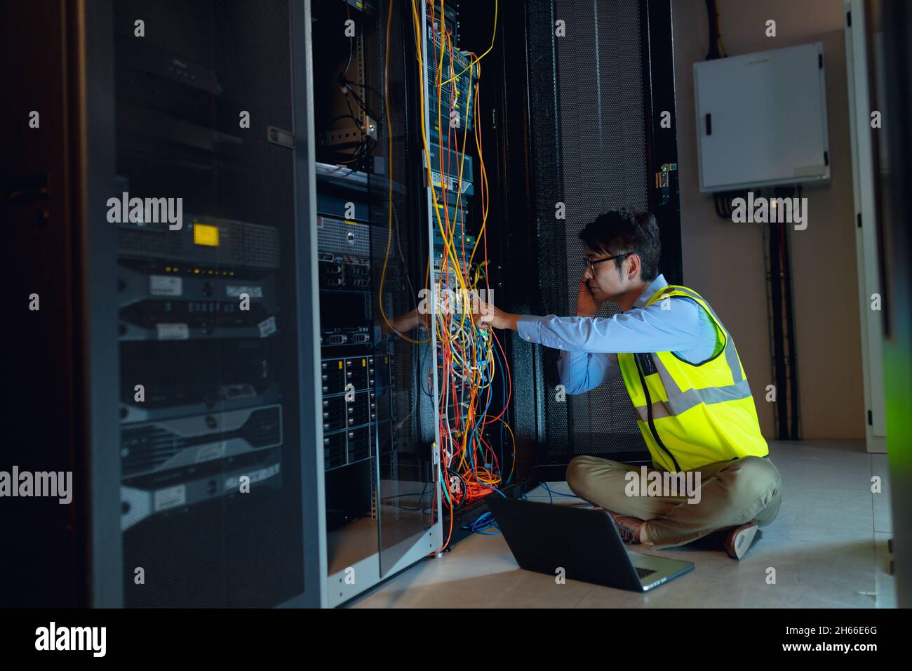 Asian male engineer with laptop talking on smartphone while inspecting ...