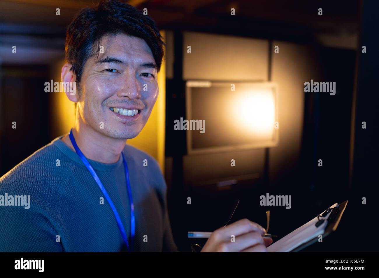 Portrait of asian male engineer smiling while writing on clipboard in ...