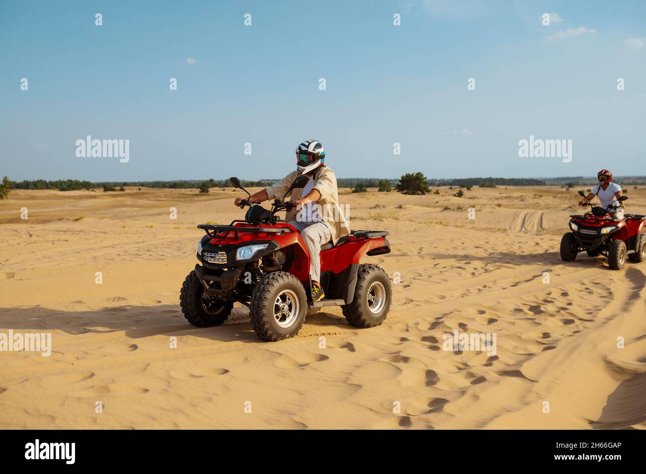 Men in helmets and glasses ride on atv in desert Stock Photo - Alamy
