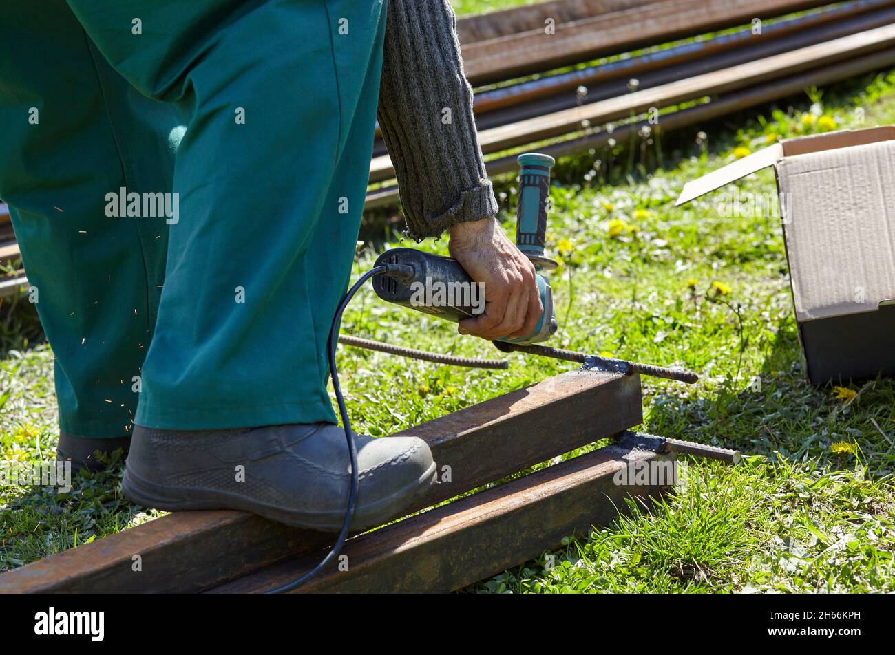 Man grinds a metal product with angle grinder outdoors. Metal ...