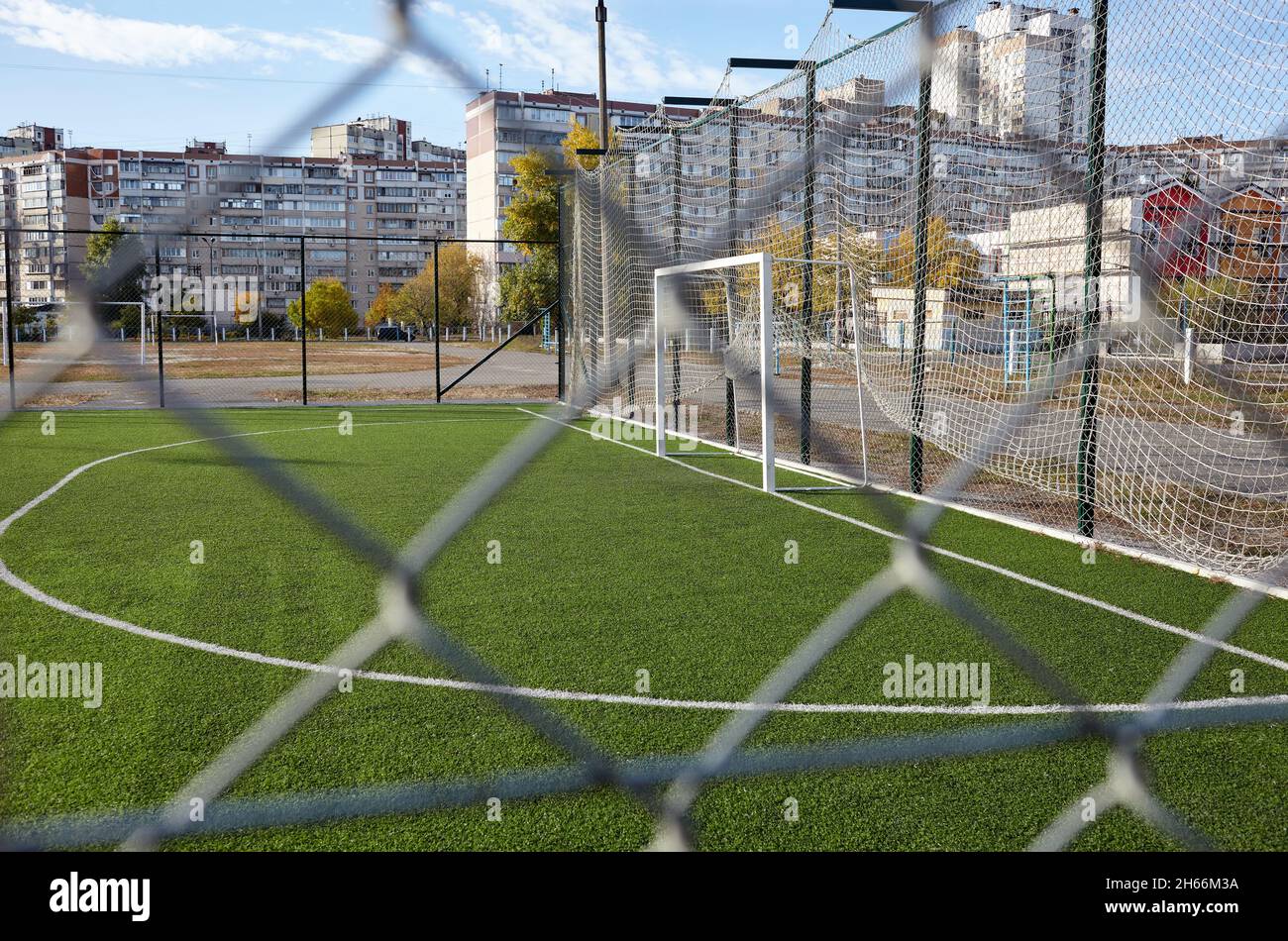 Lawn field for playing football behind the green fence mesh. Close-up ...