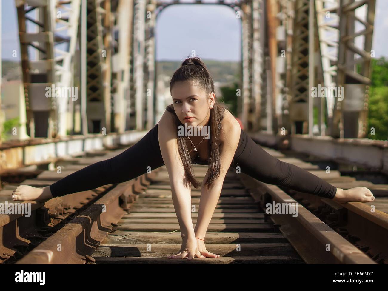 Closeup of a young Hispanic girl doing a leg split on the railways at ...