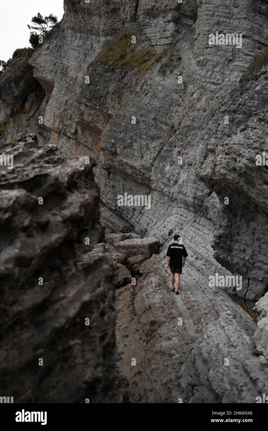 Vertical shot of a man walking along a narrow gorge in the mountain ...