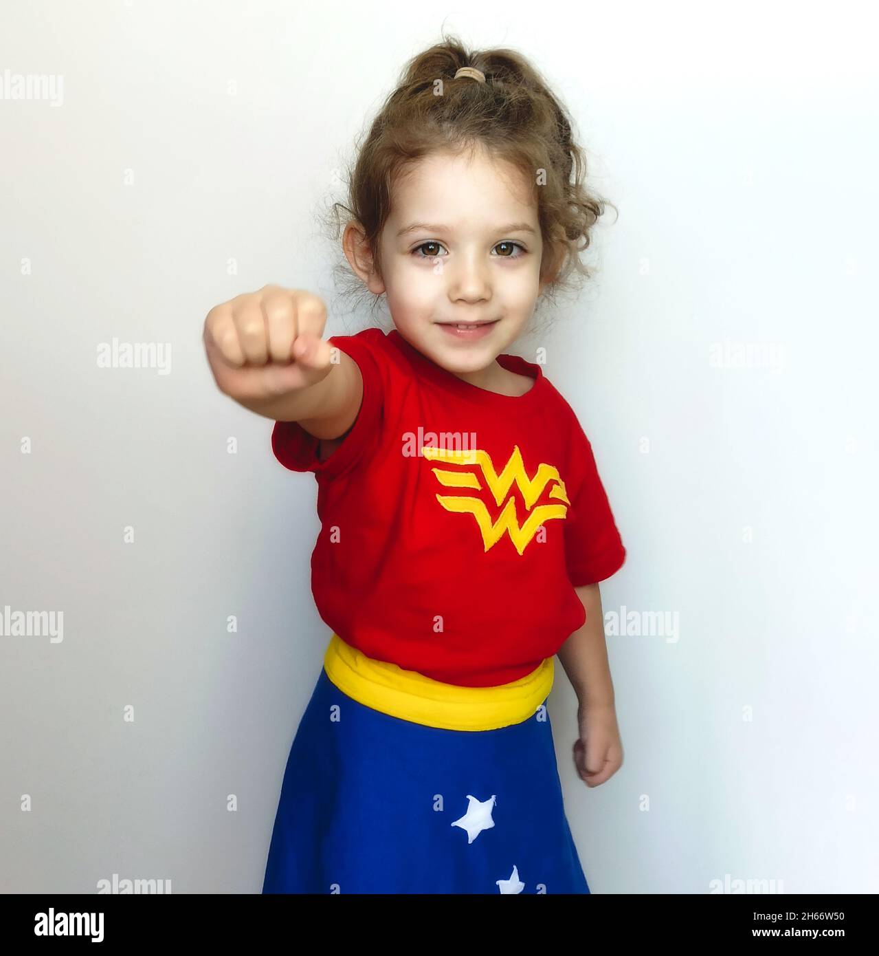 Portrait of a young cute girl posing as a super hero with Wonder Woman ...