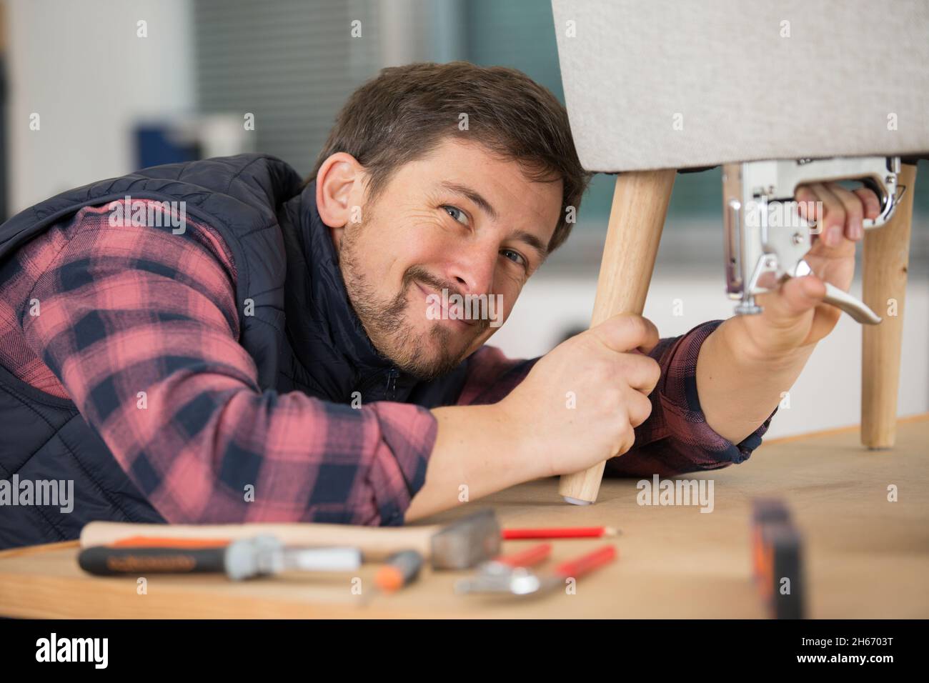happy man upholstering a round stool seat Stock Photo - Alamy