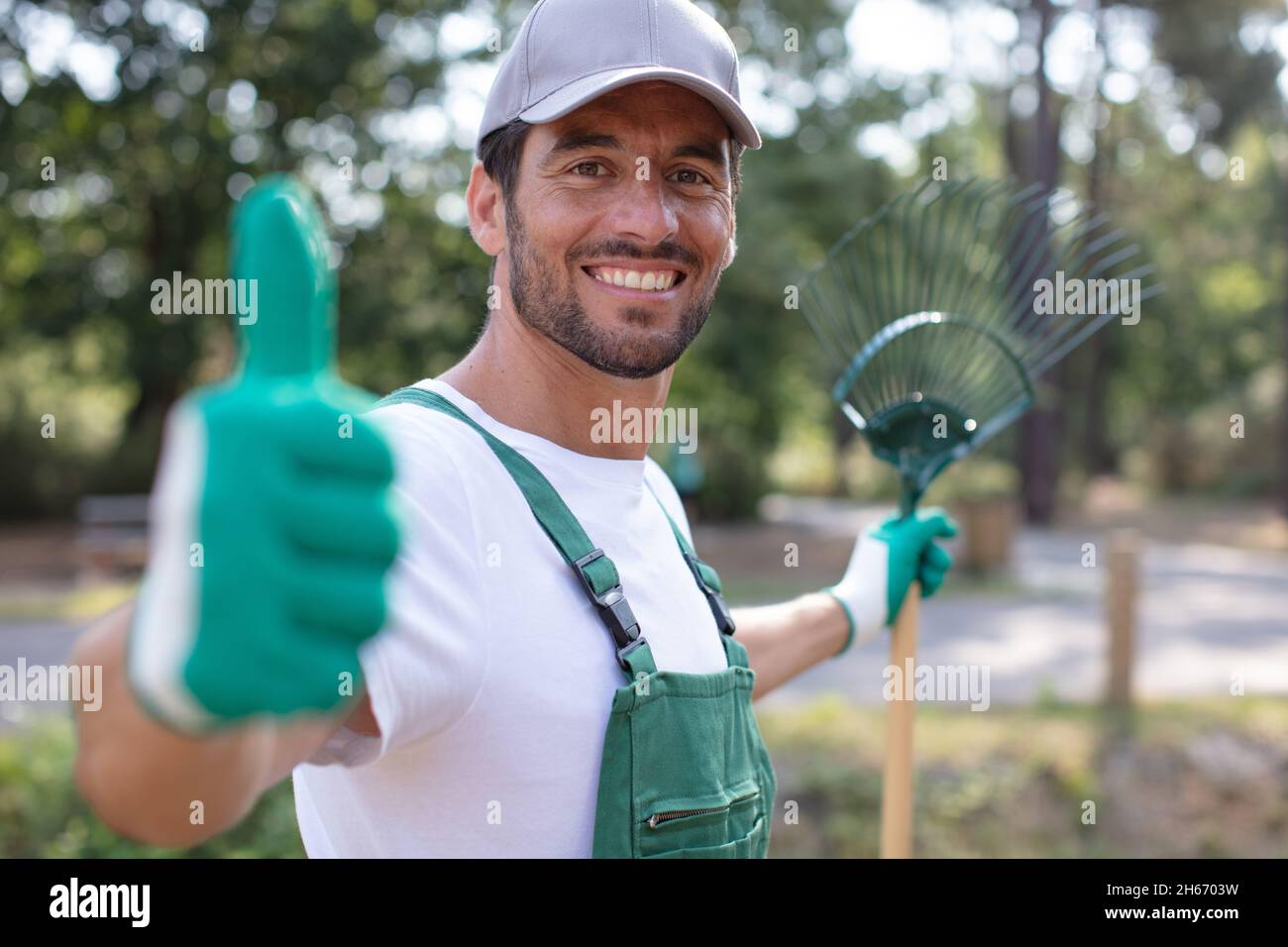 man with rake for autumn leaves clean-up showing thumb-up Stock Photo ...