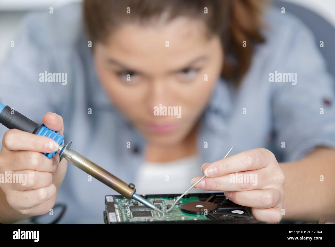 young female electronic engineer soldering computer motherboard in ...