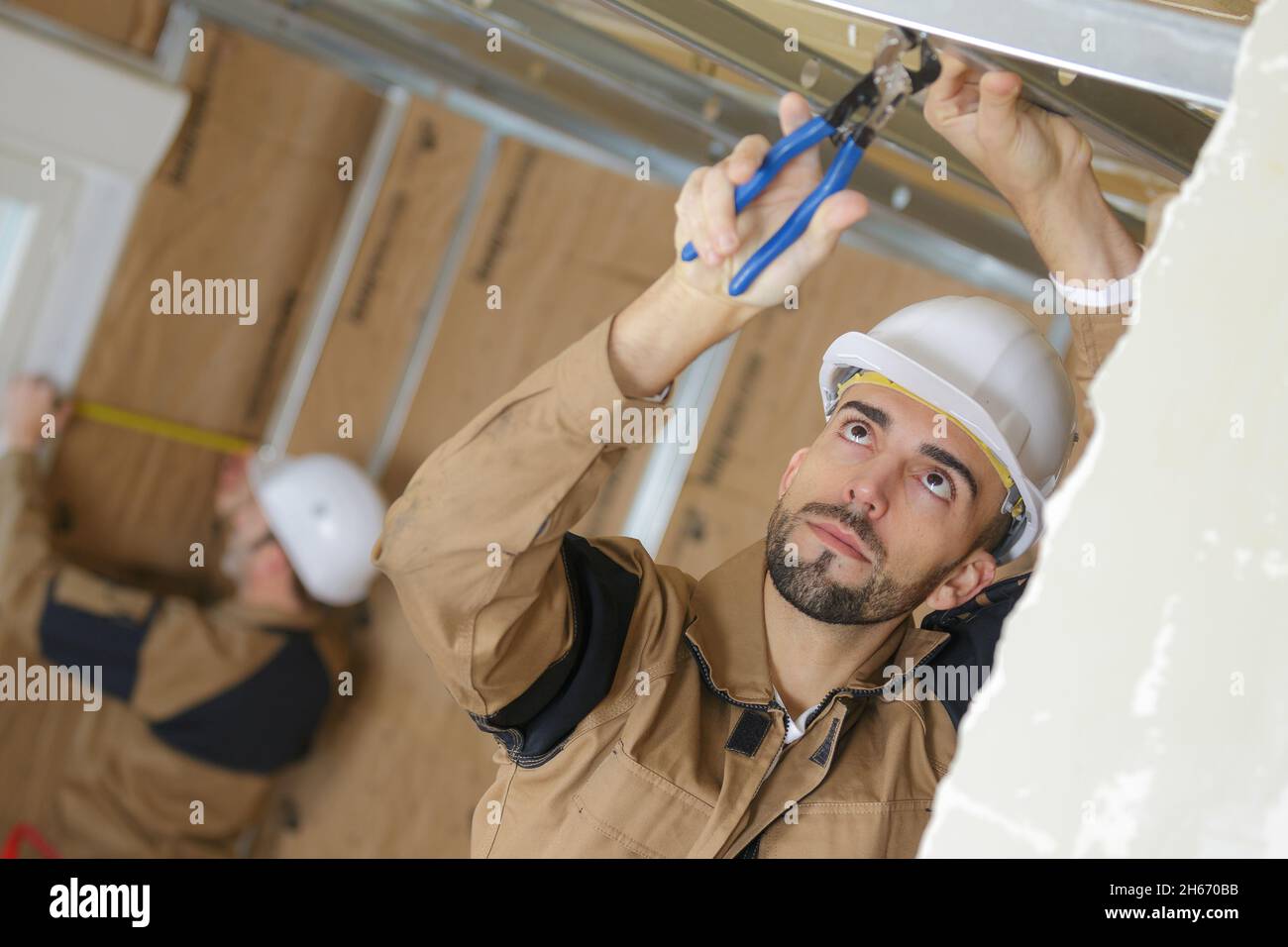 builder using tool to fix ceiling indoors Stock Photo - Alamy