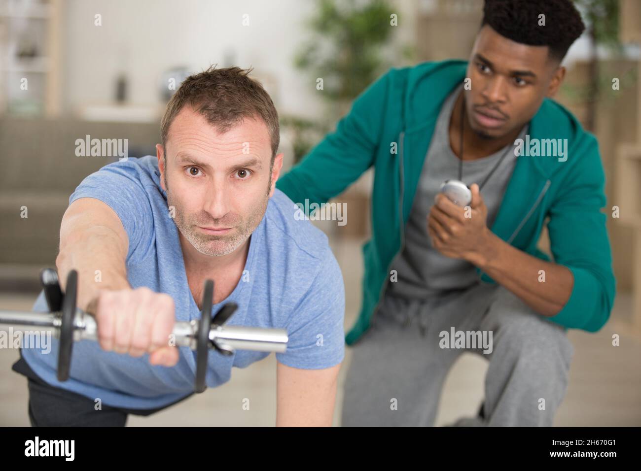 man lifting weights and man assisting Stock Photo - Alamy