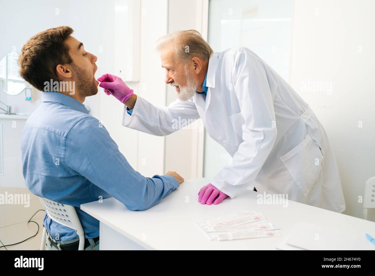 Side view of focused mature adult male doctor taking swab sample of ...