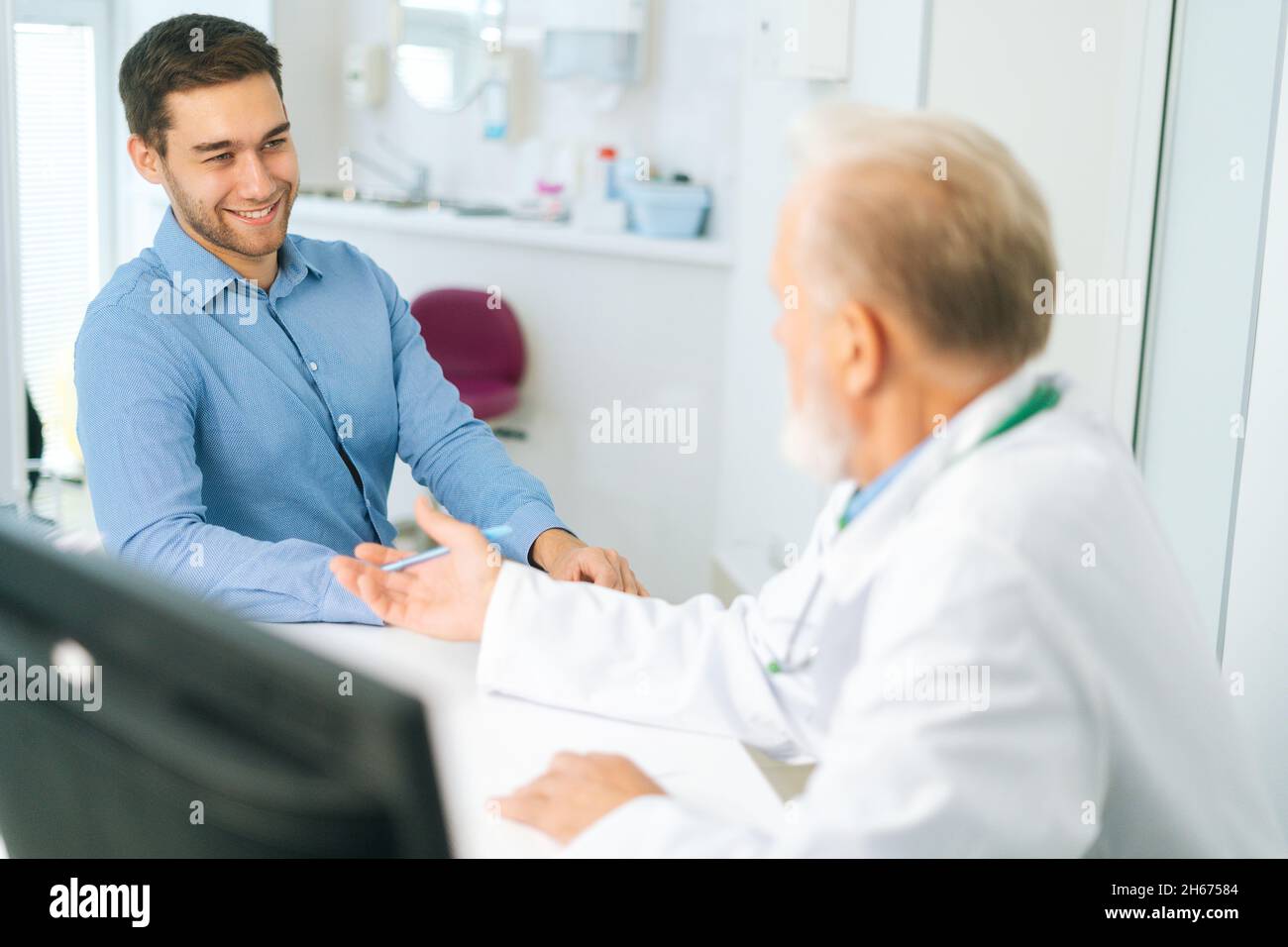 View from back to cheerful young man patient listening senior male ...