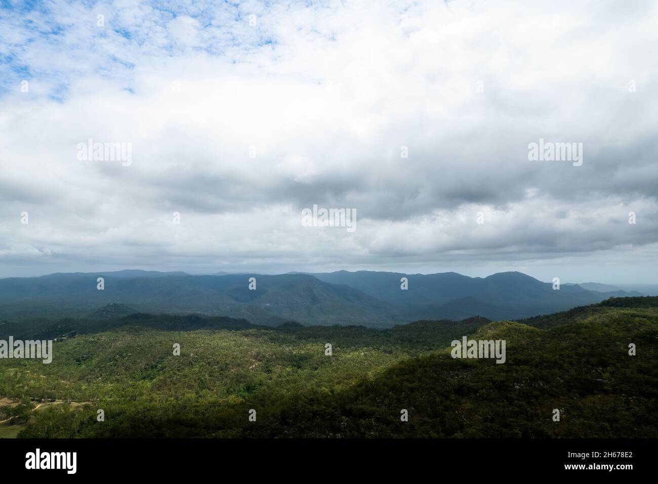 Aerial view of a forested mountain range with patches of sunlight under ...