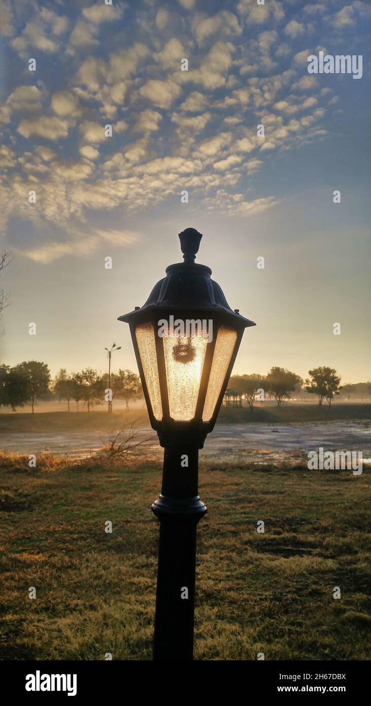 Vertical shot of an outdoor lamp post in the park against a cloudy sky ...