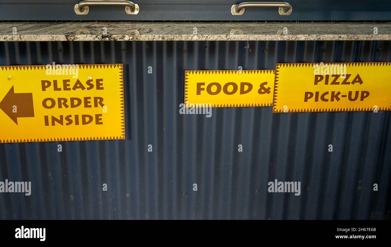 Orange and brown signs on the front of a serving counter at a country ...