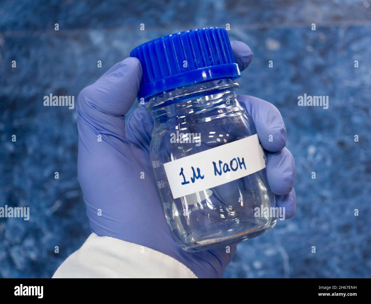 The scientist holds in his hand with a glove, a closed flask with a ...