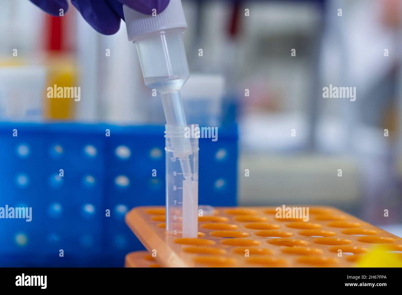 Doctor dripping clear liquid into test tube on laboratory desktop while ...