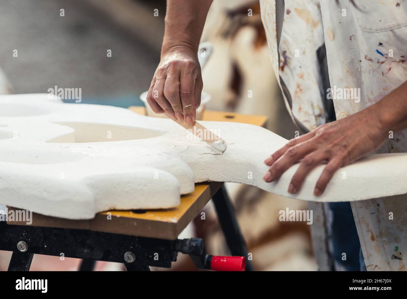 Hands of an adult woman shaping a piece of polystyrene using cream ...
