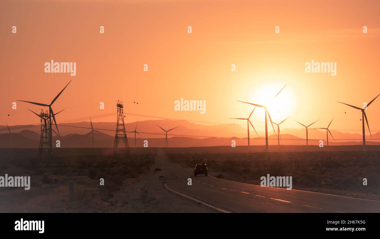 Car driving into sunset with windmills and electricity pylons Stock ...