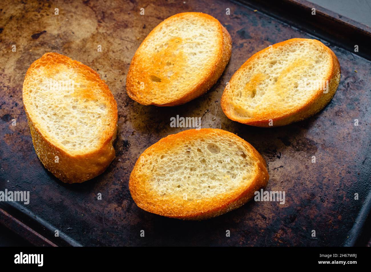 Toasted Slices of French Bread on a Sheet Pan: Sliced baguette drizzled ...