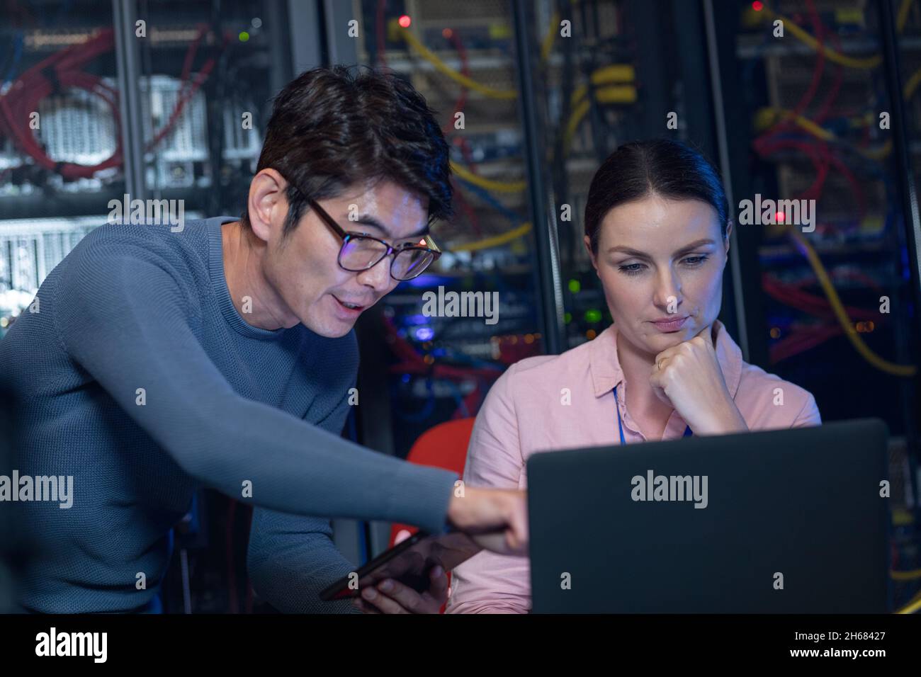 Diverse male and female engineers discussing over a laptop in computer ...