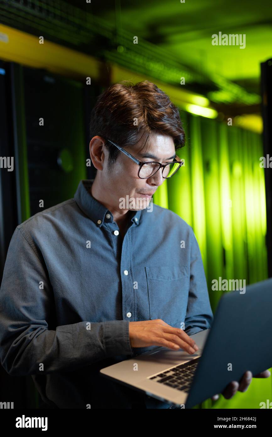 Asian male engineer using laptop in computer server room Stock Photo ...