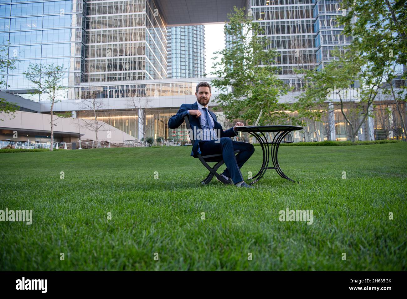 Portrait of business man sitting on modern outdoor working place ...