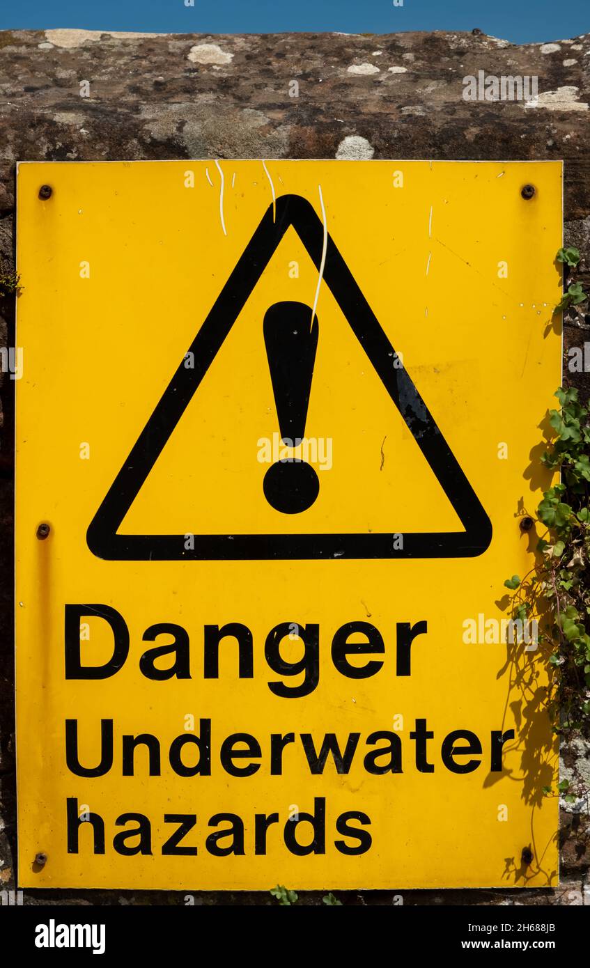A yellow Danger Underwater Hazard warning sign fixed to a brick wall ...