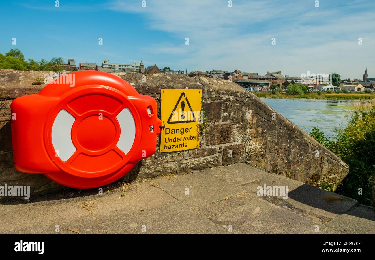 A red life preserver and yellow Danger Underwater Hazard sign fixed to ...