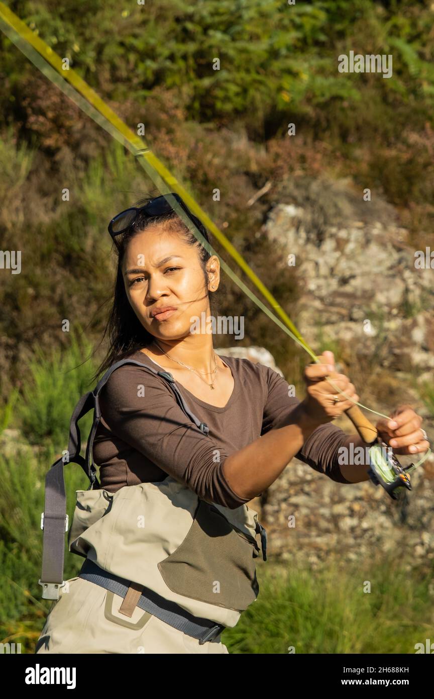 A young asian female fly fishing on a river on a summers evening Stock ...