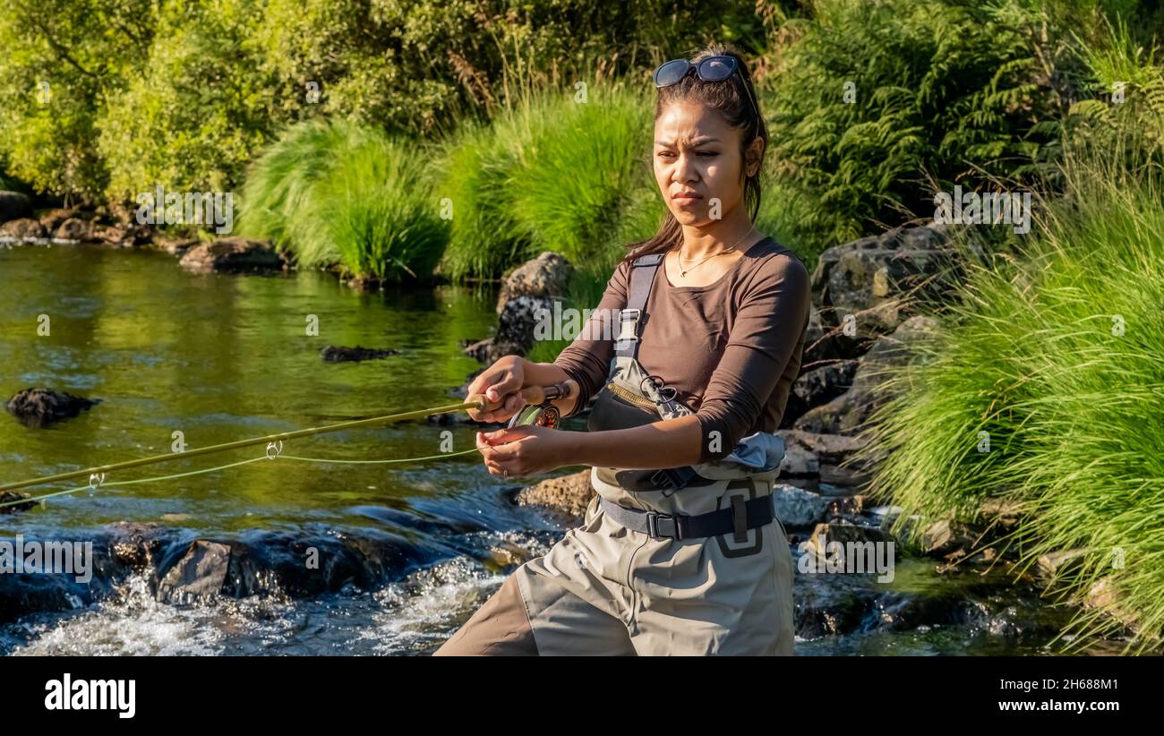 A young asian female standing fly fishing in a riffle on a river Stock ...