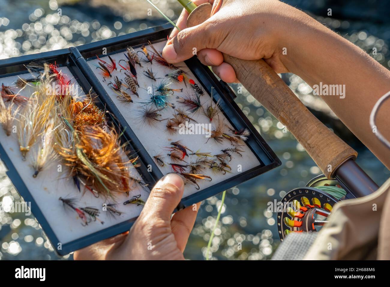 A close up of an asian female selecting fly fishing flies from a box ...