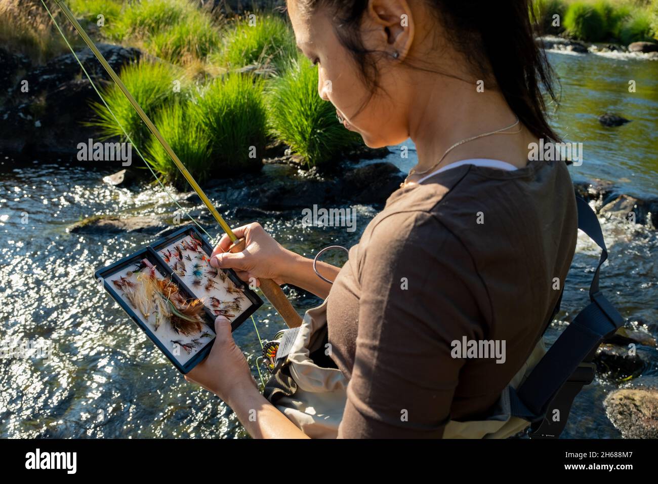 A close up of an asian female selecting fly fishing flies from a box ...