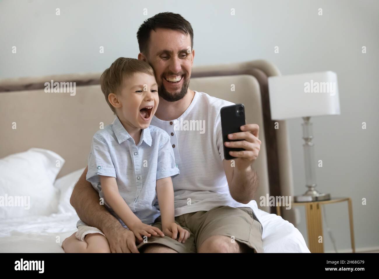 Excited laughing boy and dad using app on mobile phone Stock Photo - Alamy