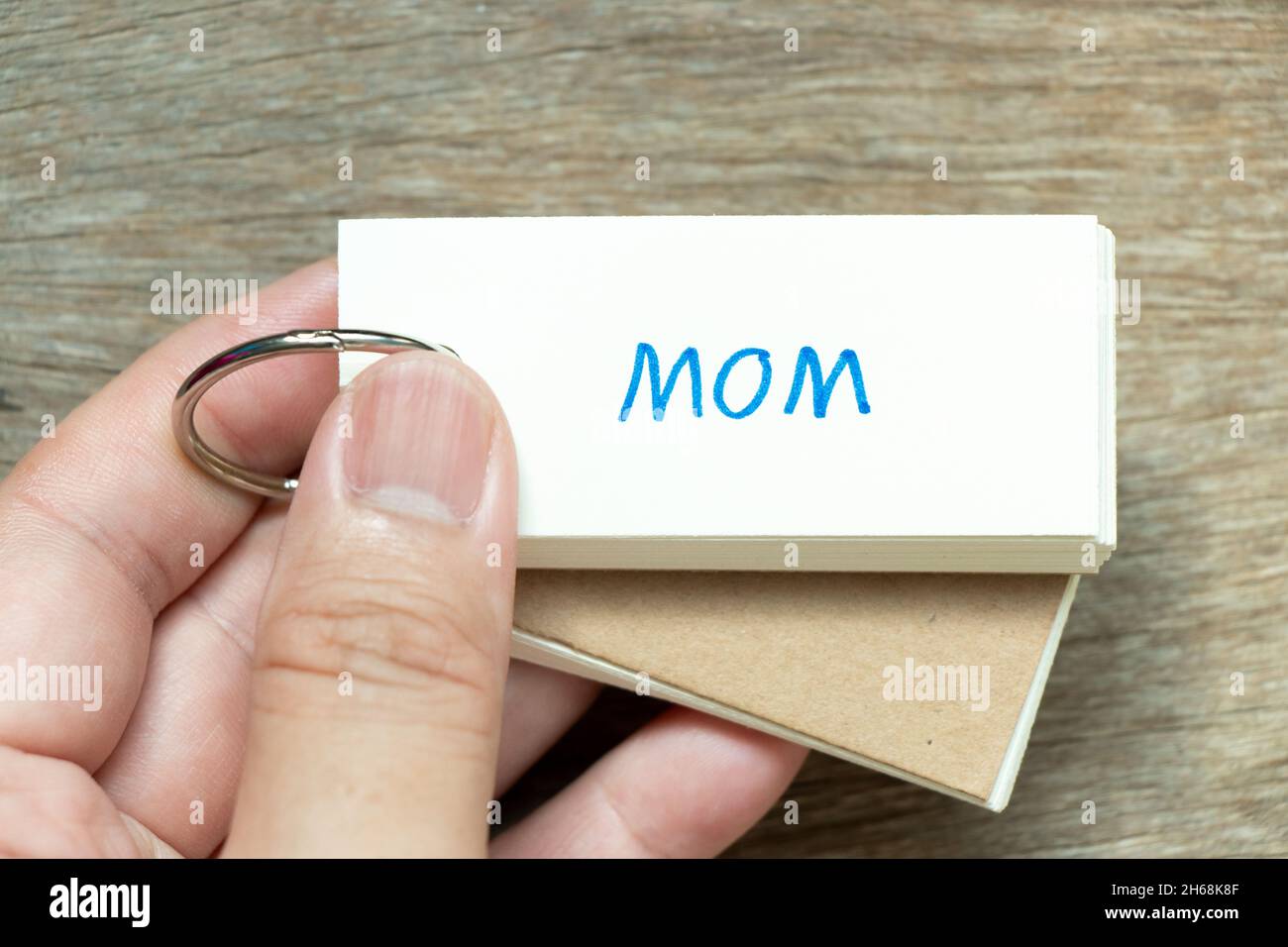 Man hold the flash card with handwriting word mom on wood background ...