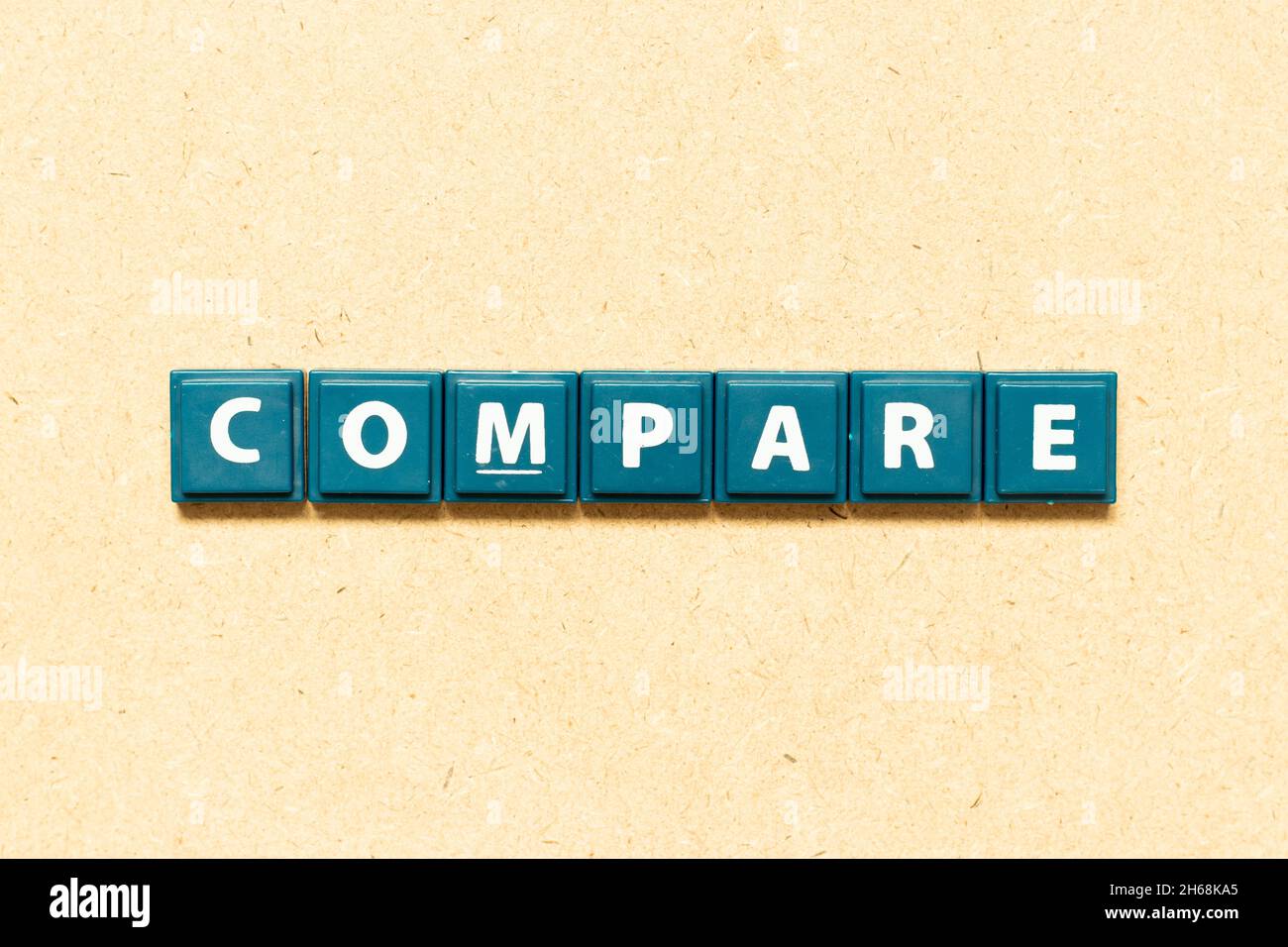 Tile alphabet letter in word compare on wood background Stock Photo - Alamy