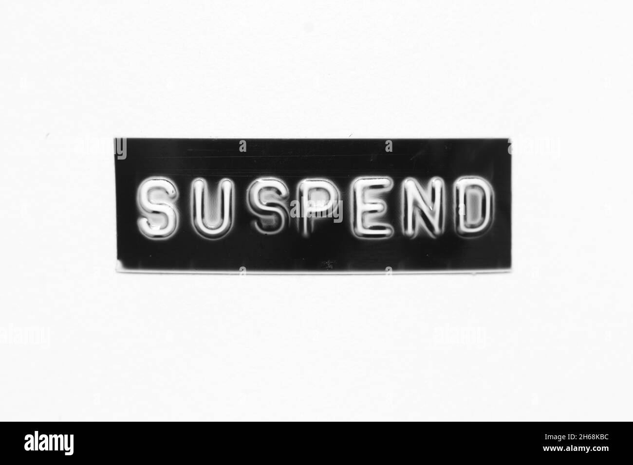 Black color banner that have embossed letter with word suspend on white ...