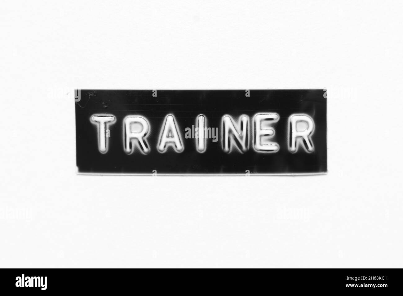 Black color banner that have embossed letter with word trainer on white ...
