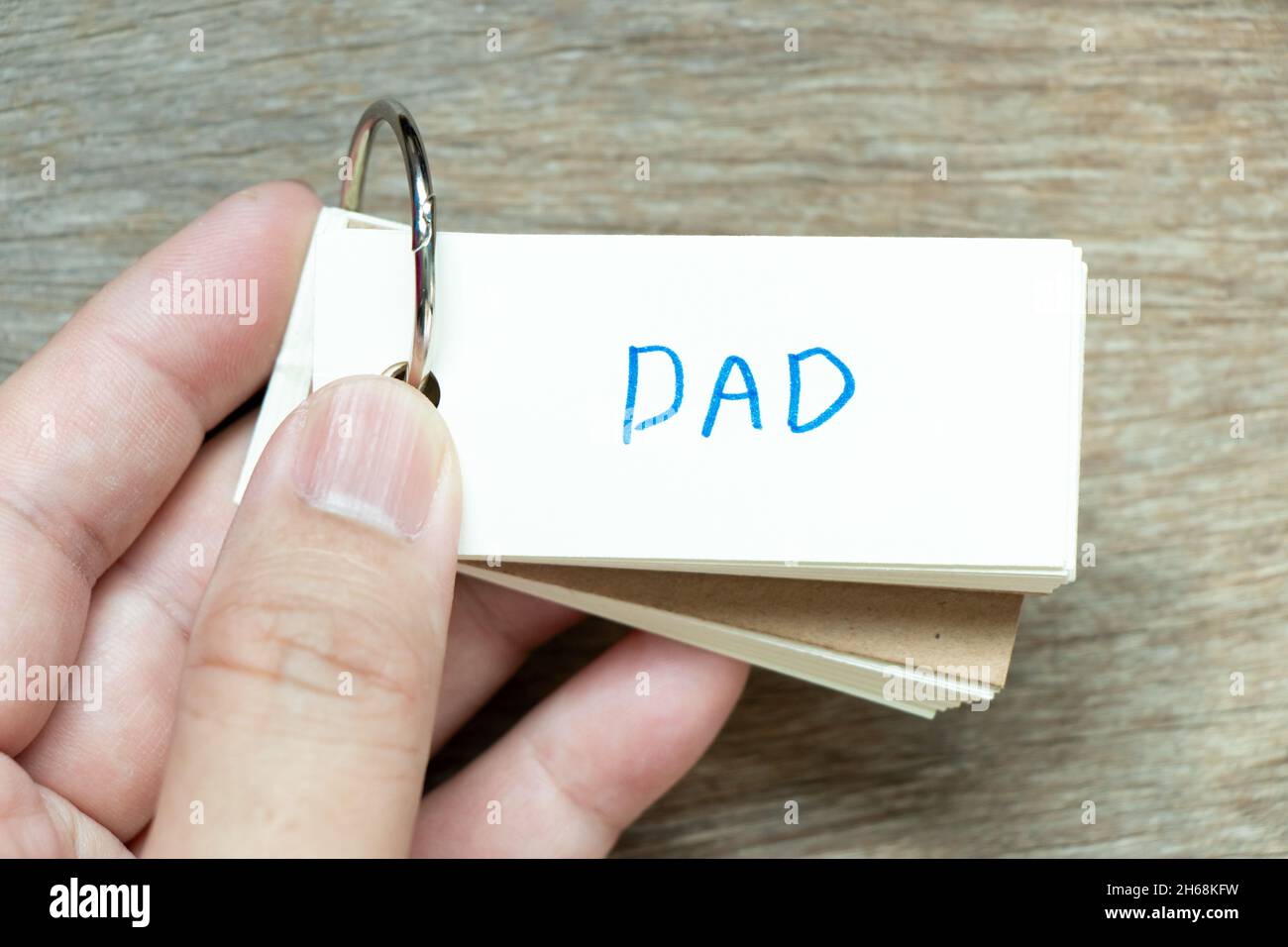 Man hold the flash card with handwriting word dad on wood background ...