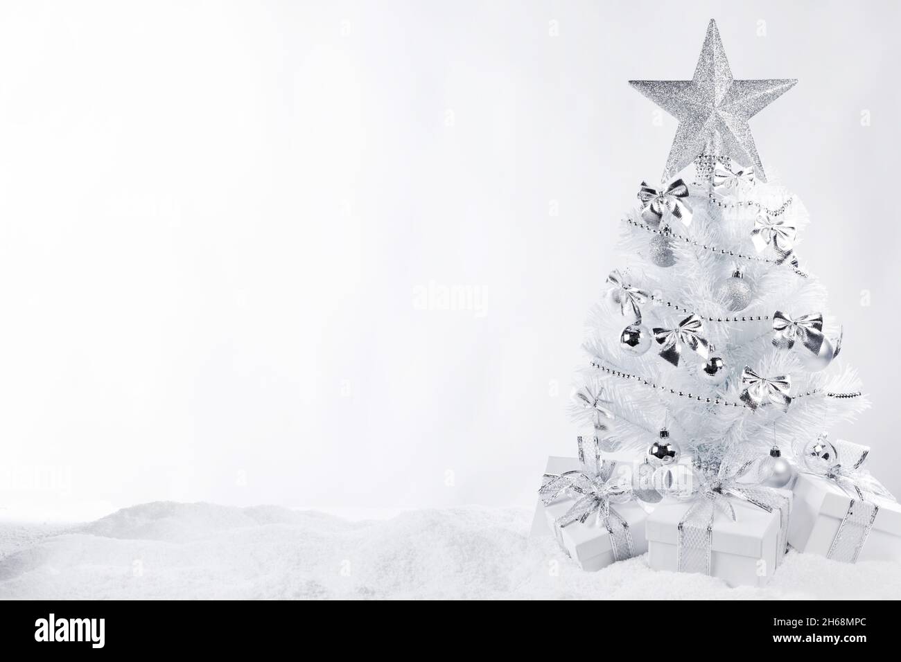 Beautiful white Christmas tree on snow decorated with balls and star ...