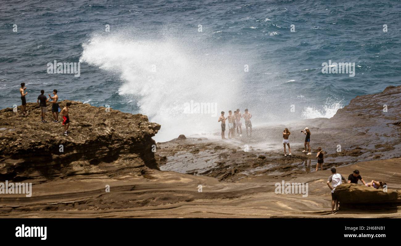 Honolulu, Hawaii - Nov 6, 2021-People stand on beach rocks as the surf ...
