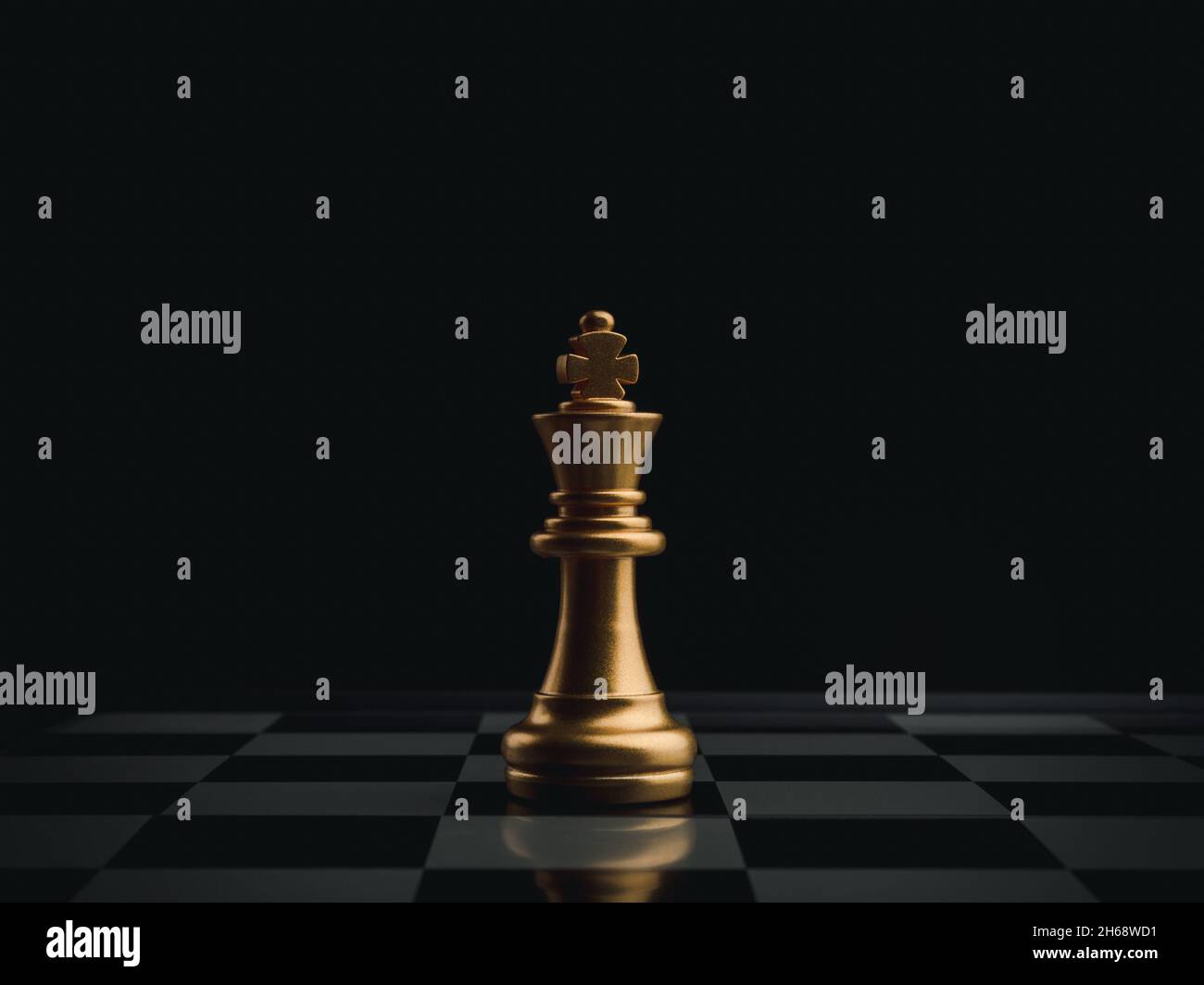 The golden king chess piece standing alone on chessboard on dark ...