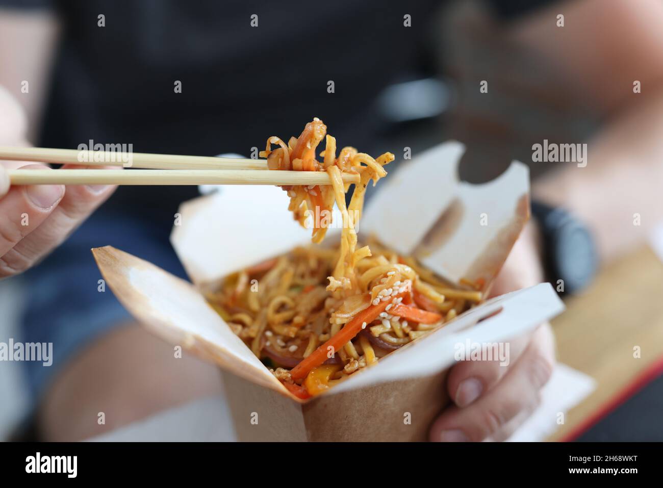 Man eating chinese food with wooden chopsticks Stock Photo - Alamy