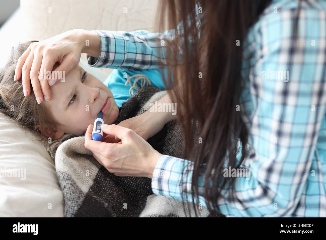irl with a thermometer in her mouth, mom is near Stock Photo - Alamy