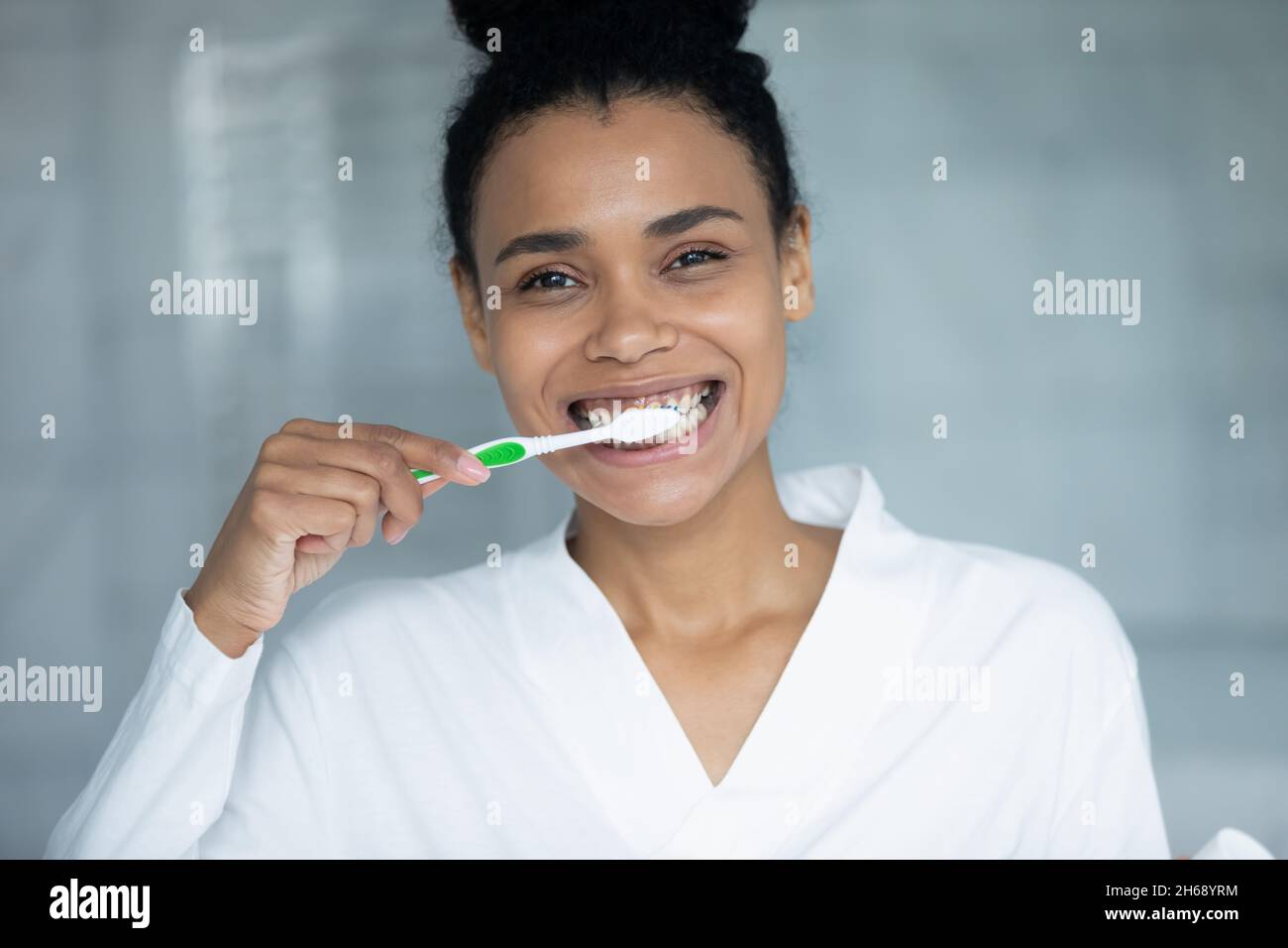 Happy young african woman brushing teeth, looking at camera Stock Photo ...
