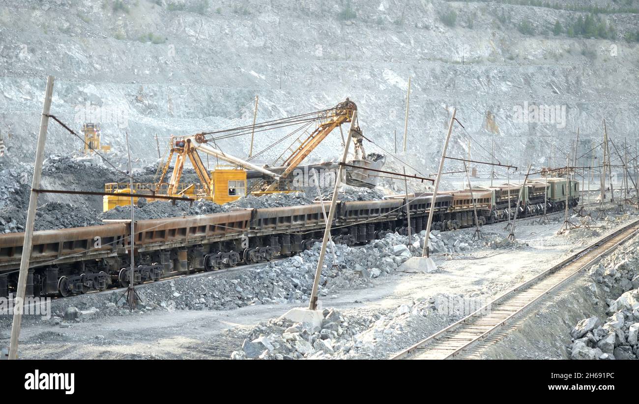 Excavator and railway with ore. Excavator fills with ore rail cars in ...