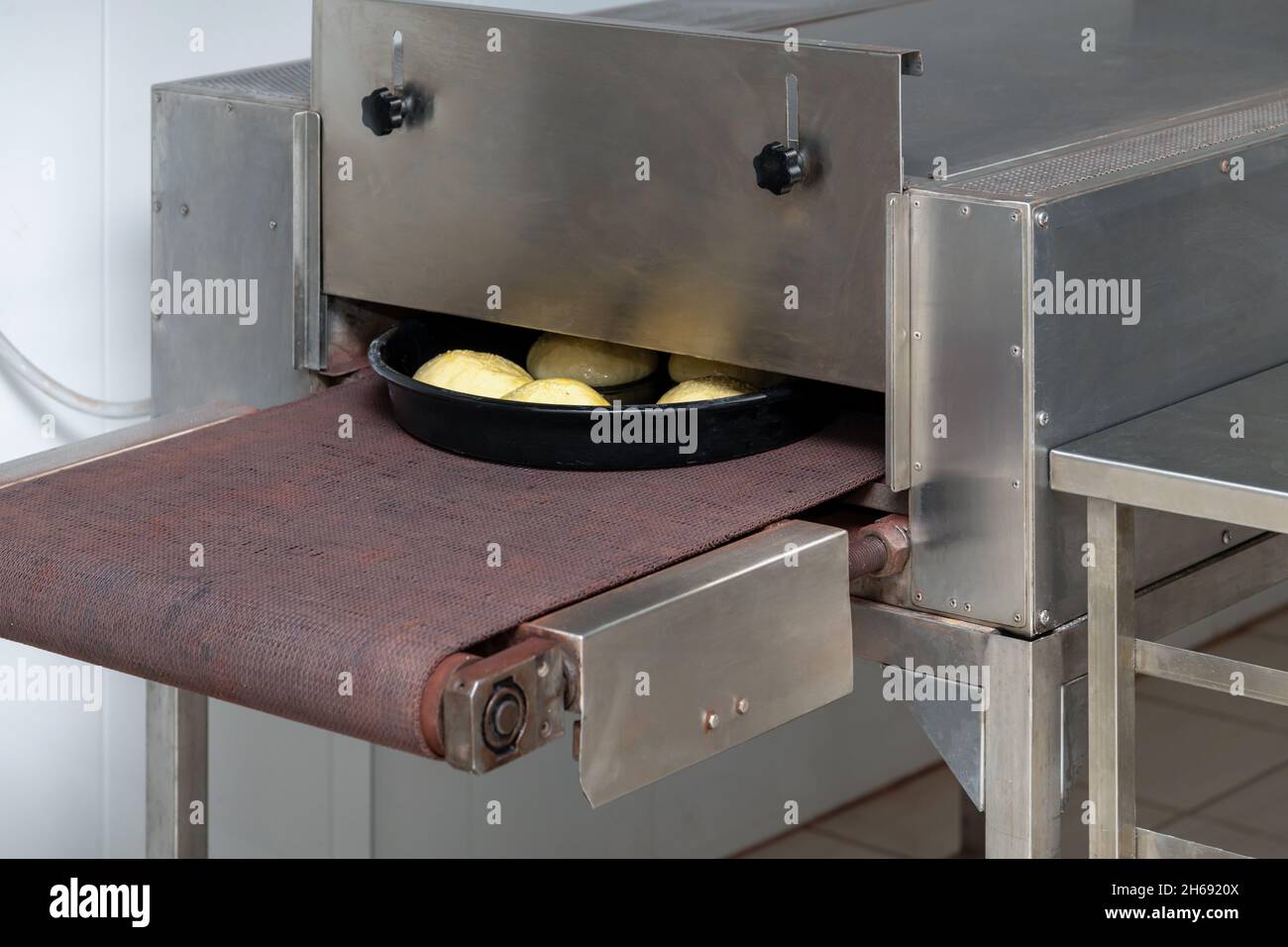Baking production line. Raw uncooked hamburger buns going to the oven ...