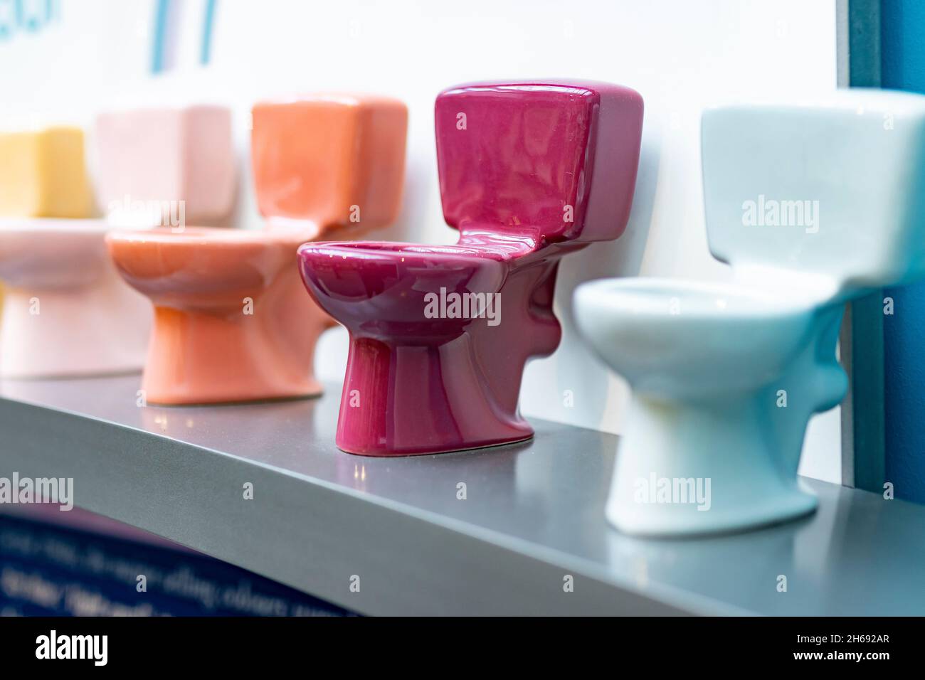row of multicoloured salesman's ceramic glazed toilet samples flushed ...