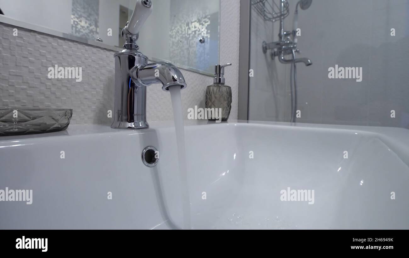 Open chrome faucet washbasin. Water flows from the tap in the modern ...