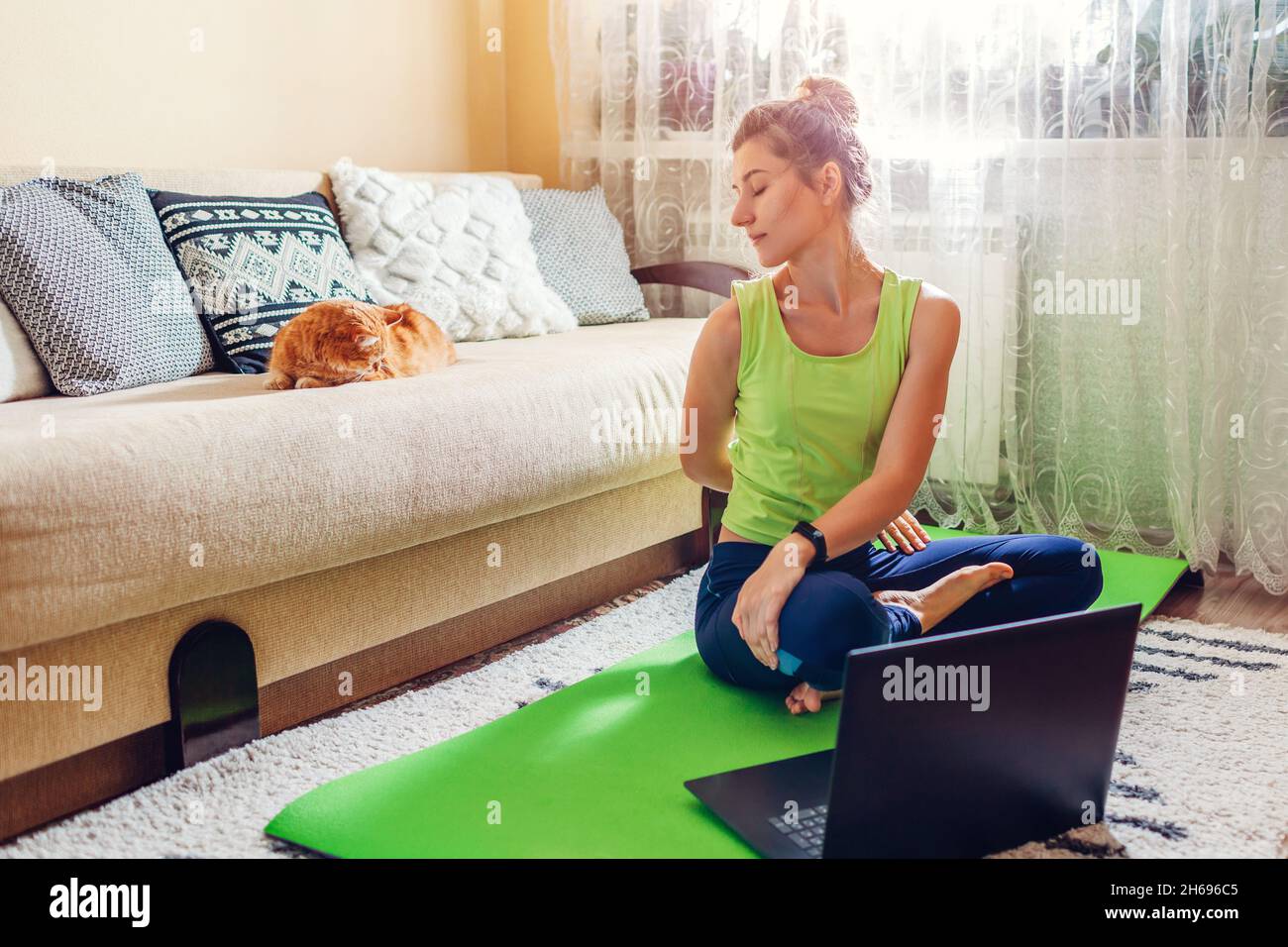 Home yoga workout during coronavirus lockdown. Seated spinal twist pose ...